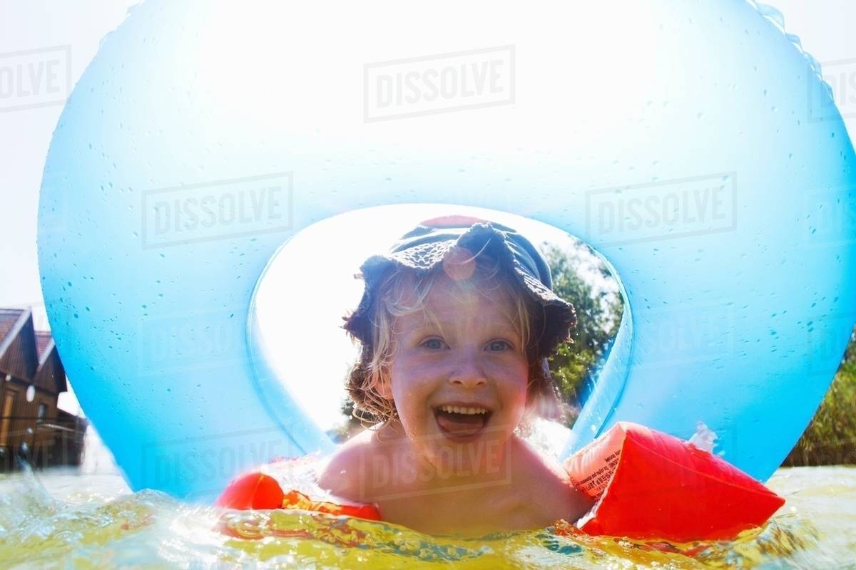 Boy playing with inner tube in pool - Stock Photo - Dissolve