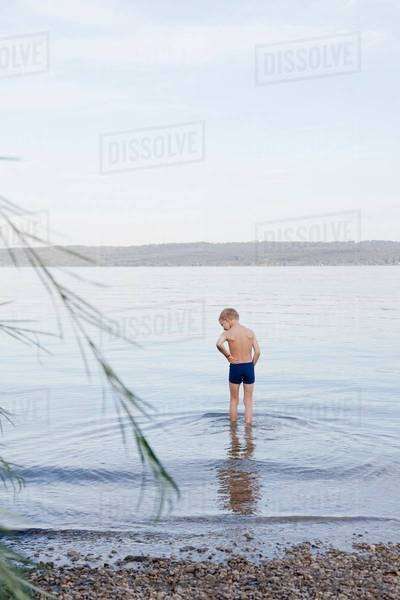 Boy wading on rocky beach - Royalty-free Stock Photo | Dissolve