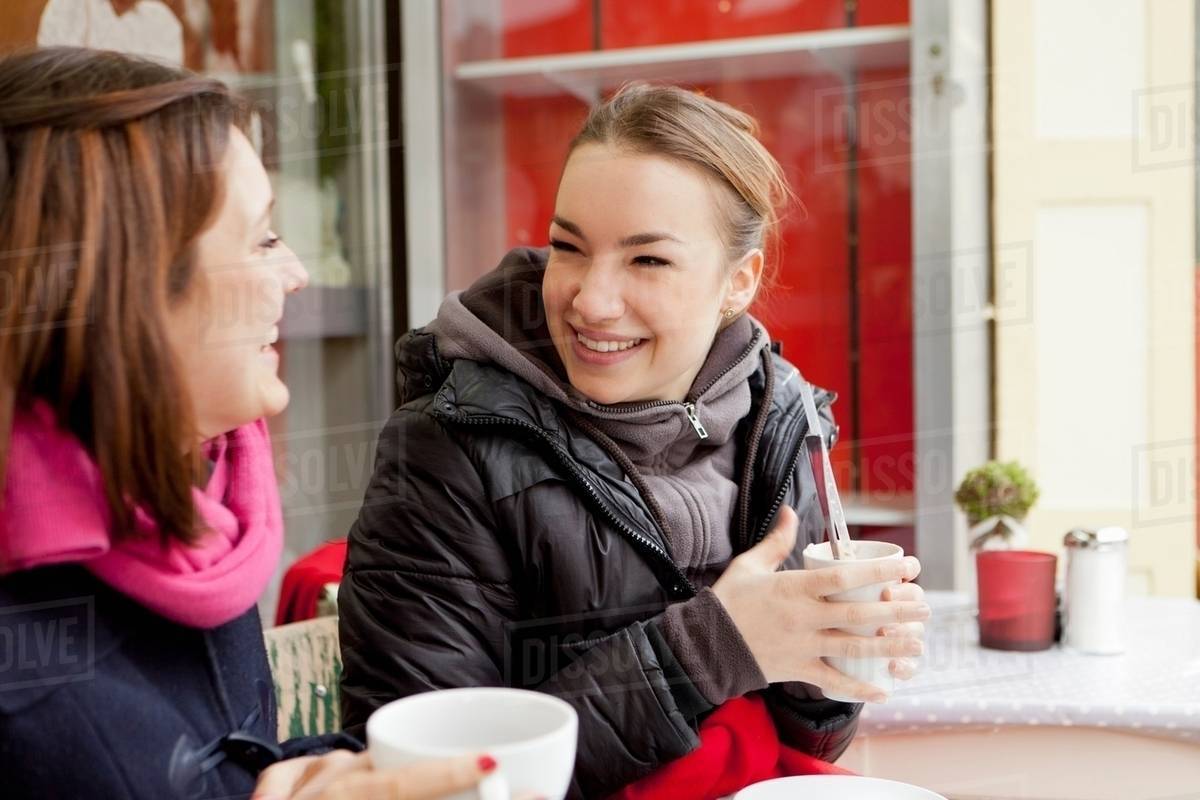 Smiling women having coffee outdoors - Stock Photo - Dissolve