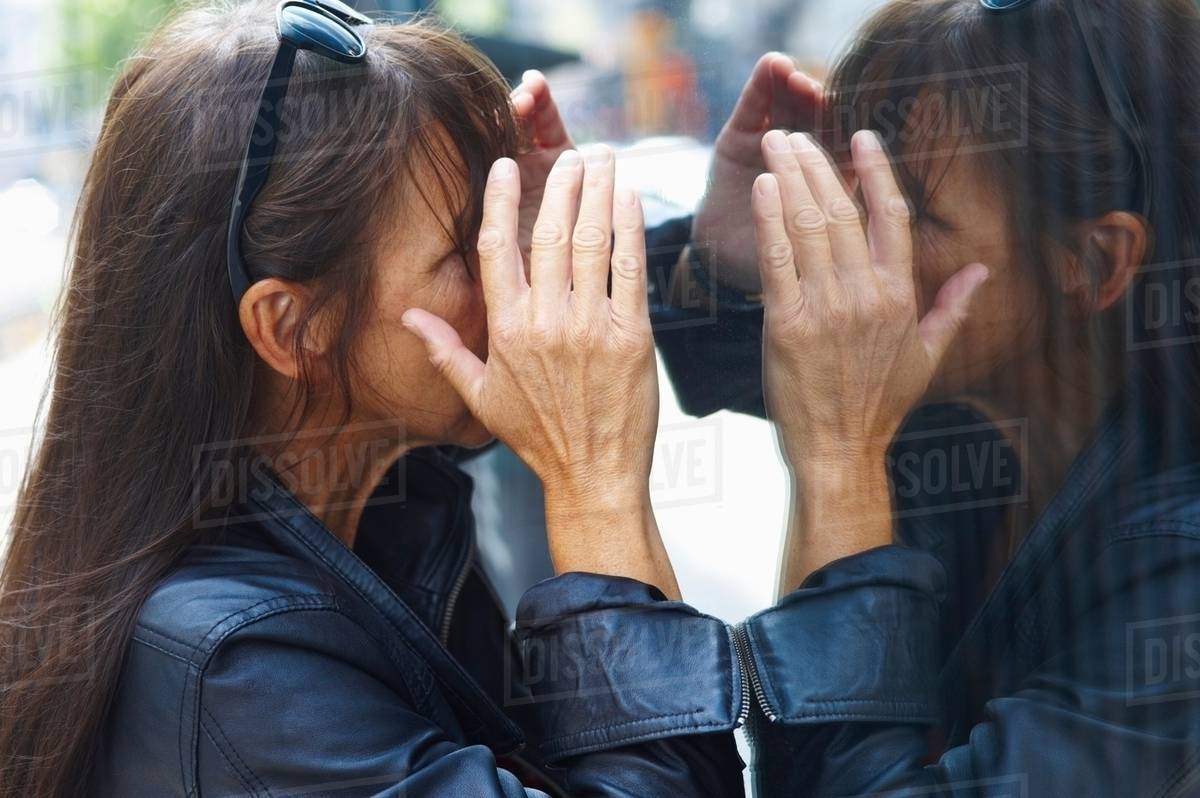 Woman peering through window - Stock Photo - Dissolve