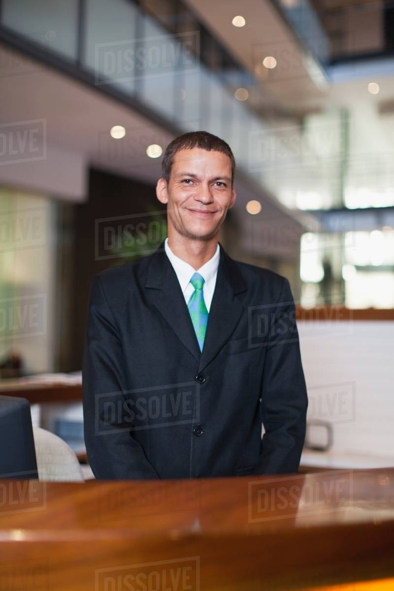 Hotel concierge smiling at desk - Stock Photo - Dissolve