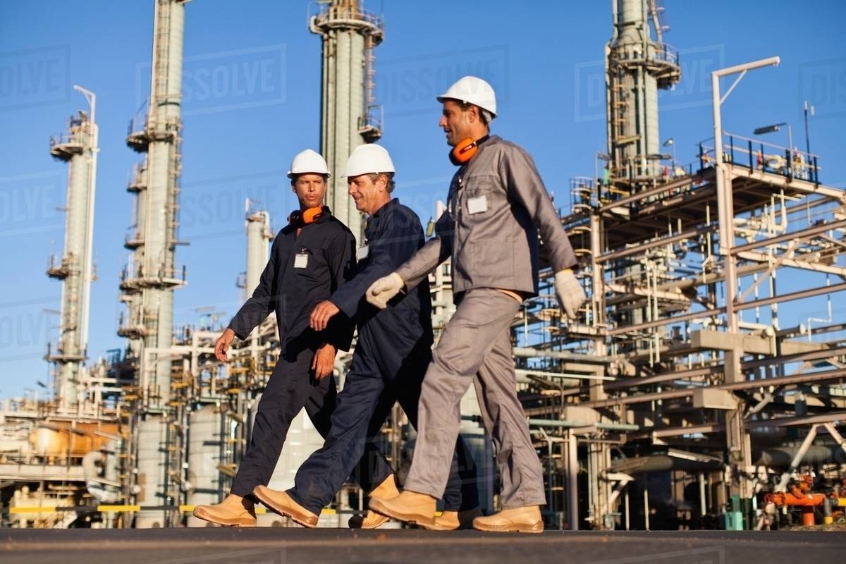 Workers walking at oil refinery - Stock Photo - Dissolve
