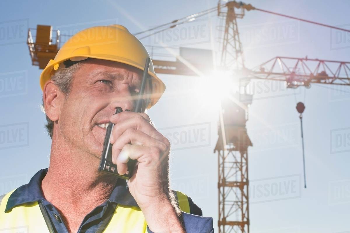 Worker using walkie talkie on site - Stock Photo - Dissolve