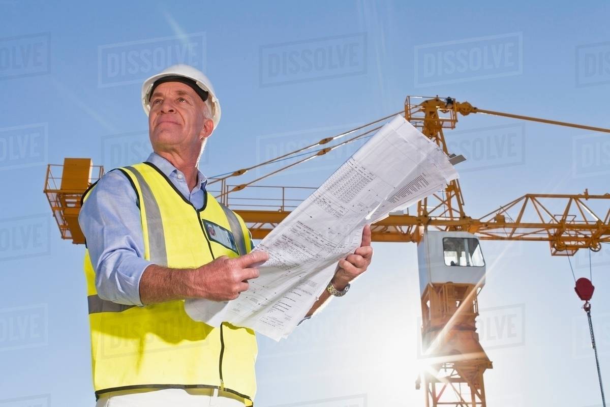 Worker reading blueprints on site - Royalty-free Stock Photo | Dissolve