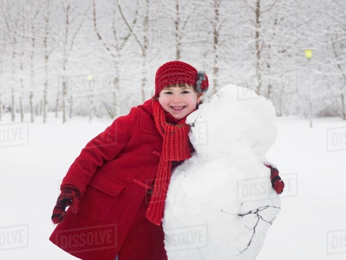Smiling girl hugging snowman outdoors - Royalty-free Stock Photo | Dissolve