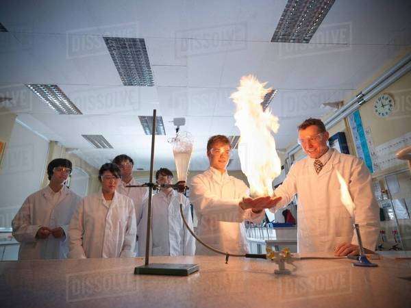 Science teacher and students conducting experiment in school laboratory ...