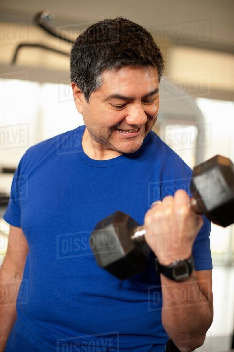 Smiling man lifting weights in gym - Royalty-free Stock Photo | Dissolve