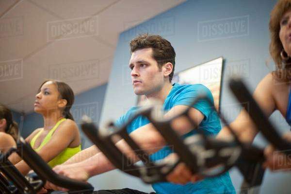 People using spin machines in gym - Stock Photo - Dissolve