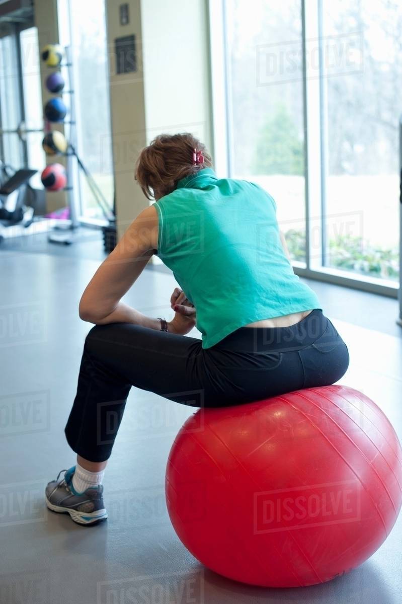 Woman using exercise ball in gym - Stock Photo - Dissolve