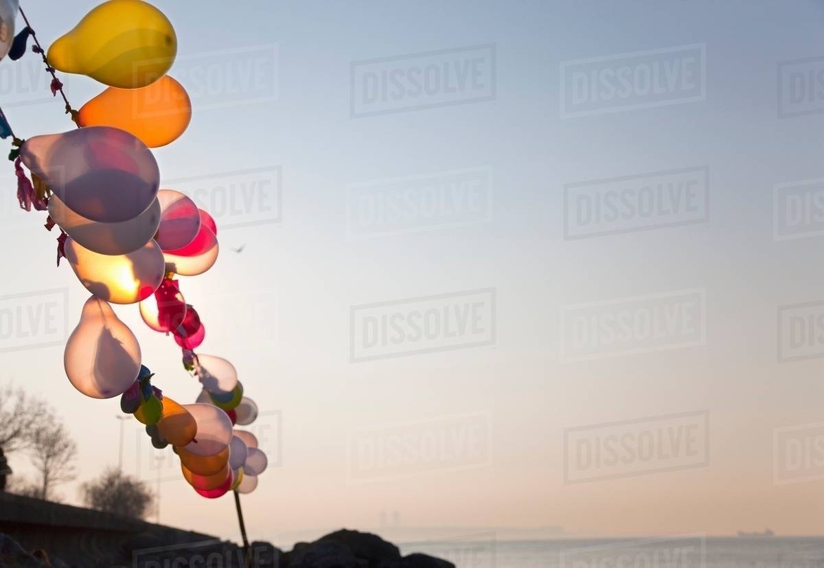 String of balloons floating in wind - Stock Photo - Dissolve