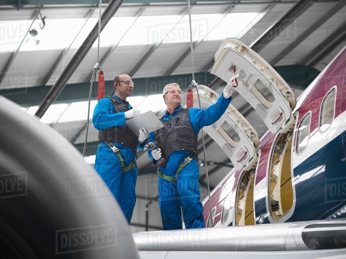 Aircraft engineers working on wing of 737 jet airplane in airport ...