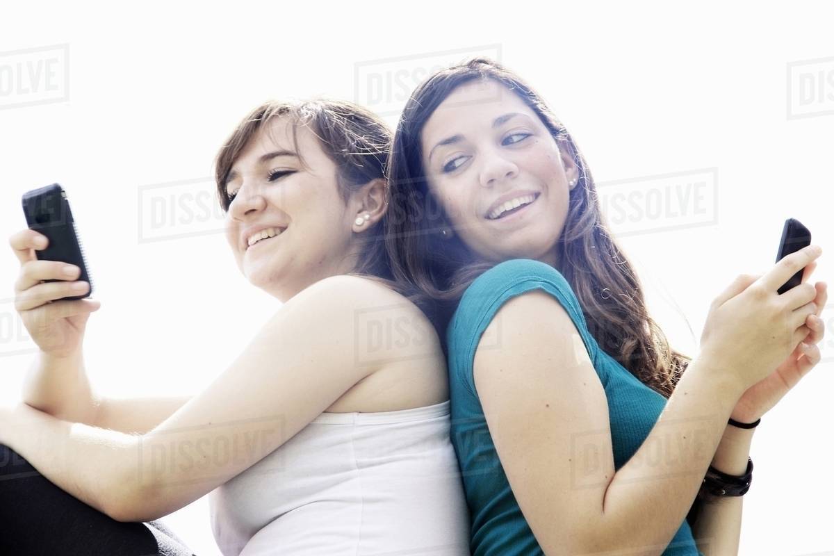Teenage girls using cell phones outdoors - Royalty-free Stock Photo ...