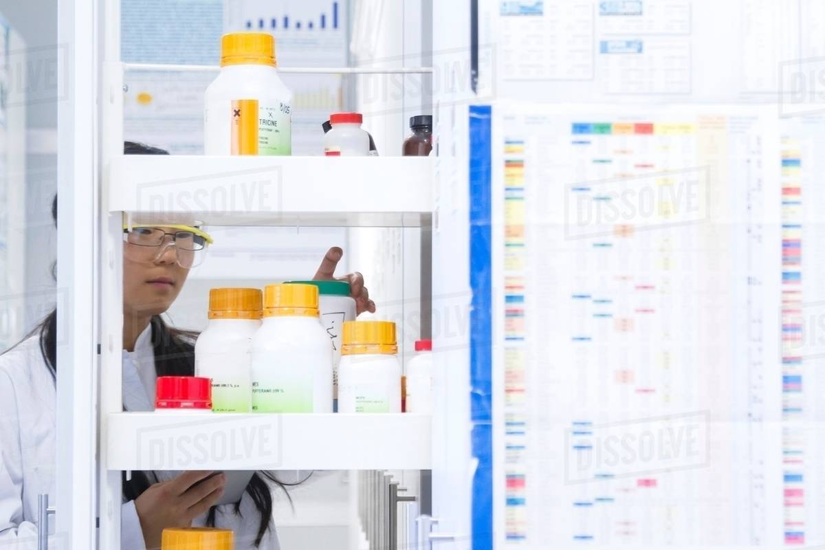 Female scientist selecting specimen jar from shelf in laboratory ...