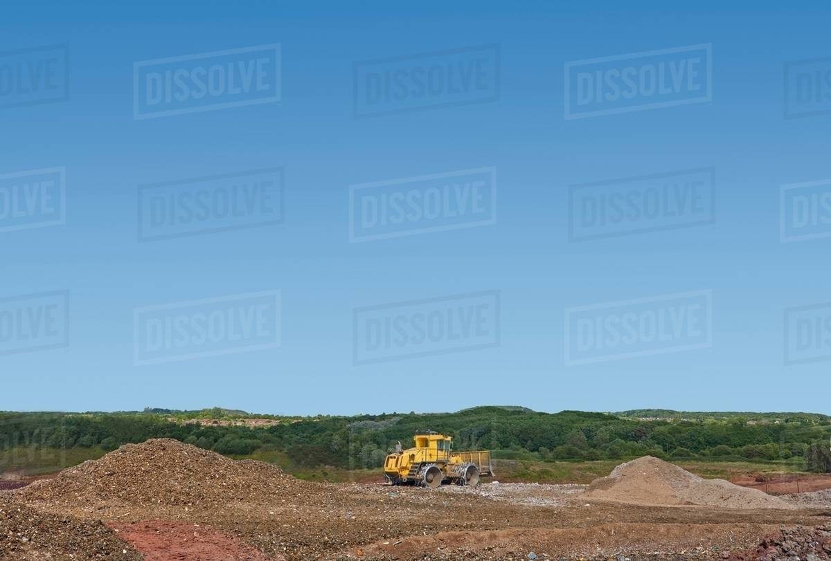 Digger burying waste on landfill site - Royalty-free Stock Photo | Dissolve