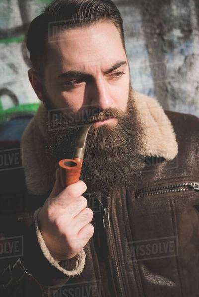 Young bearded man smoking pipe by graffiti wall - Royalty-free Stock ...