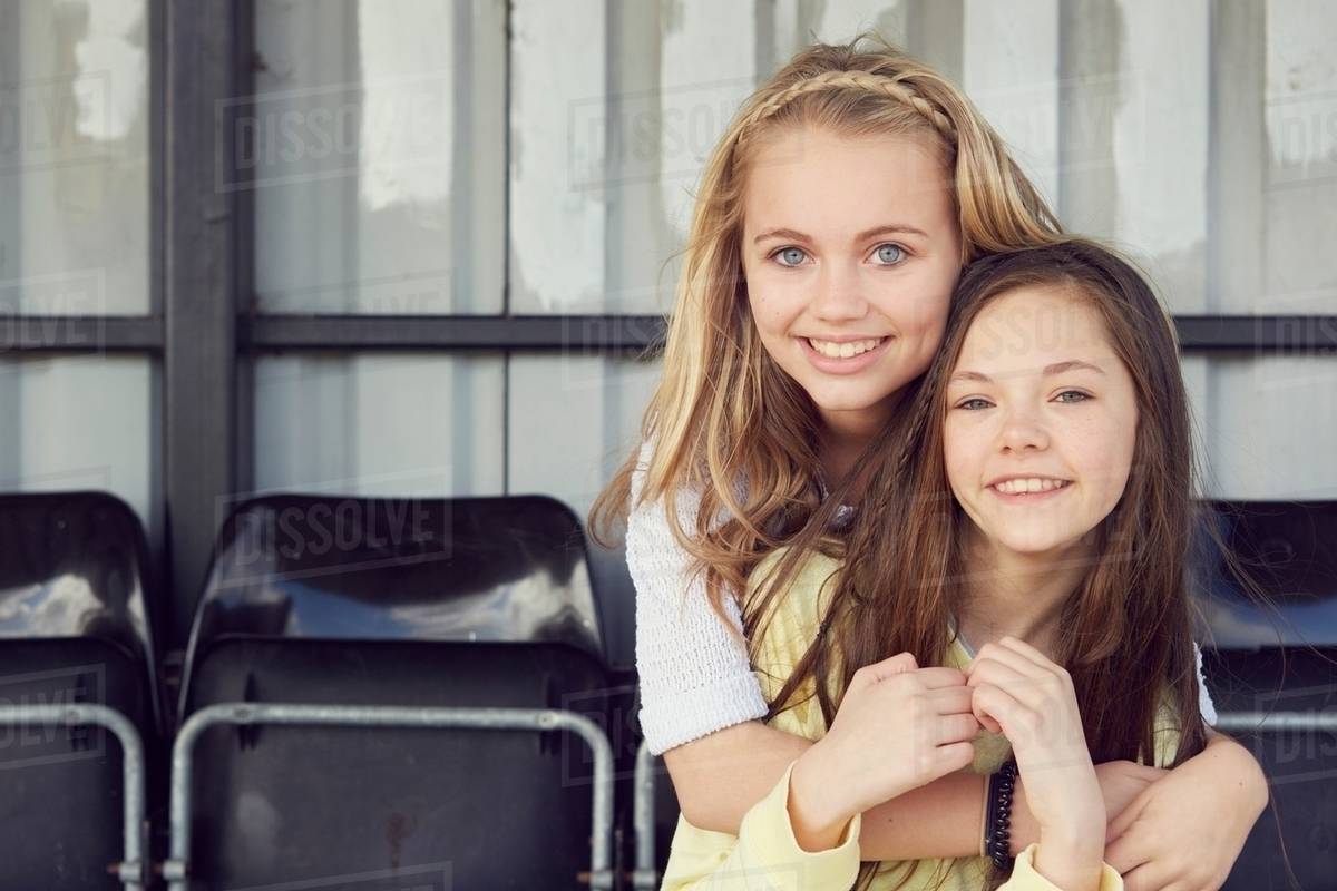 Portrait of two girls hugging in stadium stand - Stock Photo - Dissolve