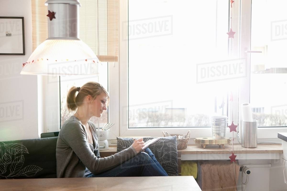 Woman in kitchen, writing - Stock Photo - Dissolve