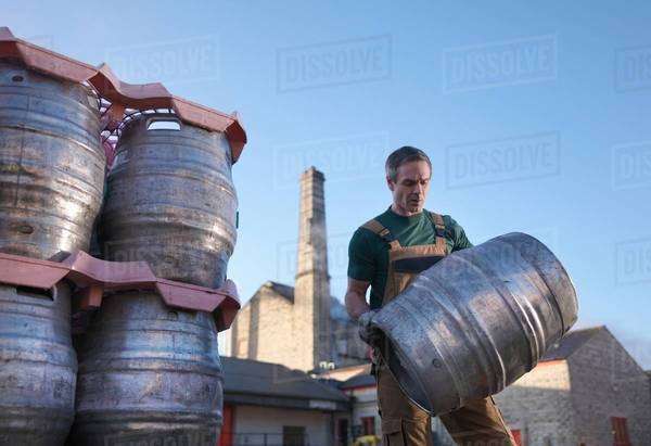 Worker carrying barrel outside brewery - Stock Photo - Dissolve