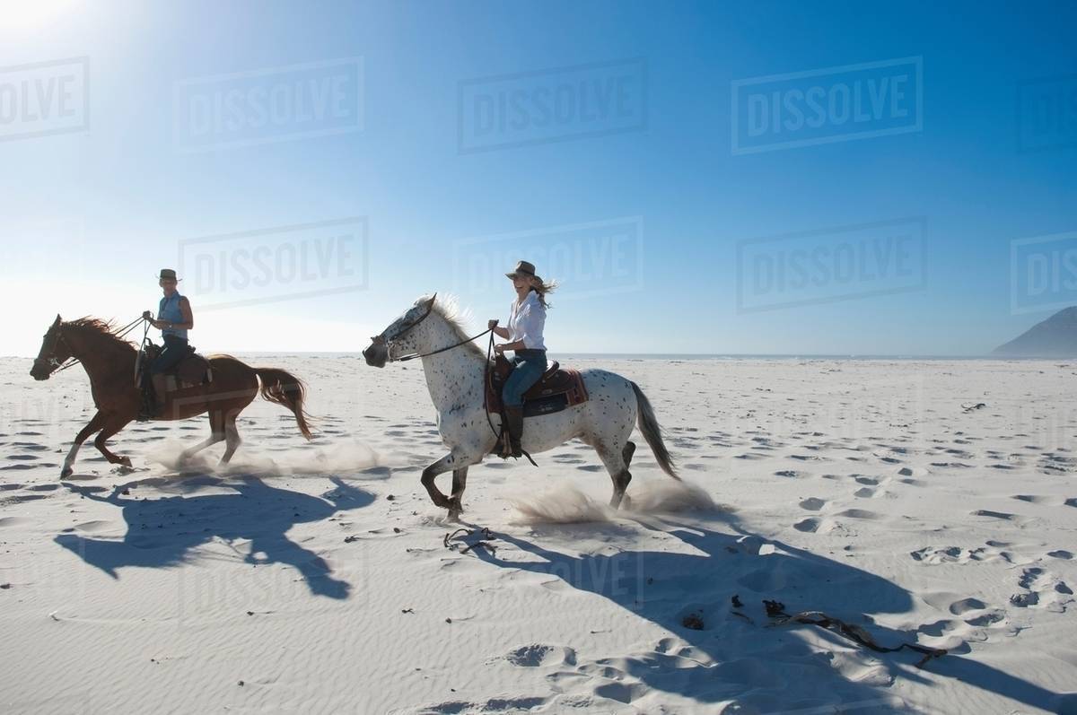 2 people riding horses in the sand - Royalty-free Stock Photo | Dissolve