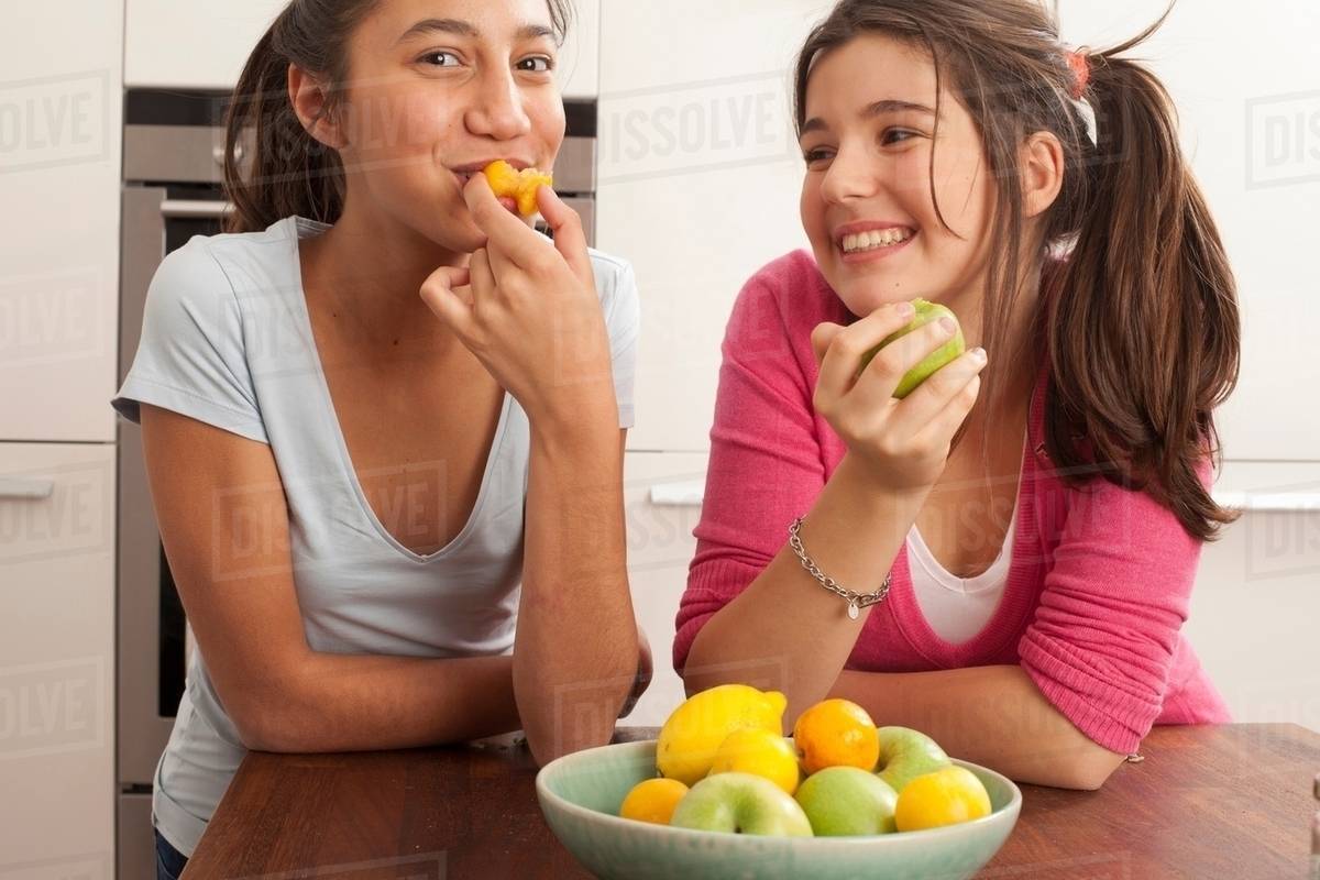 Teenage girls smiling , eating fruit - Royalty-free Stock Photo | Dissolve