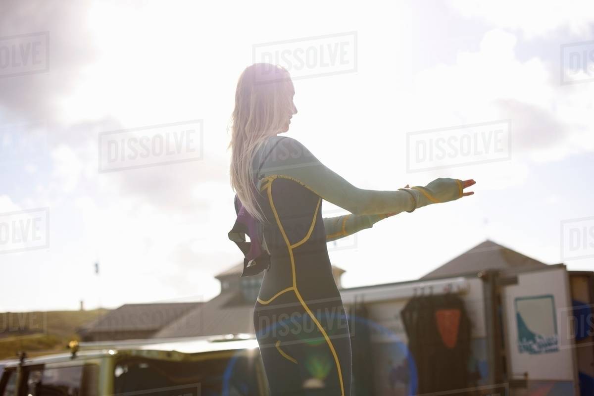 Female surfer putting on wetsuit - Stock Photo - Dissolve