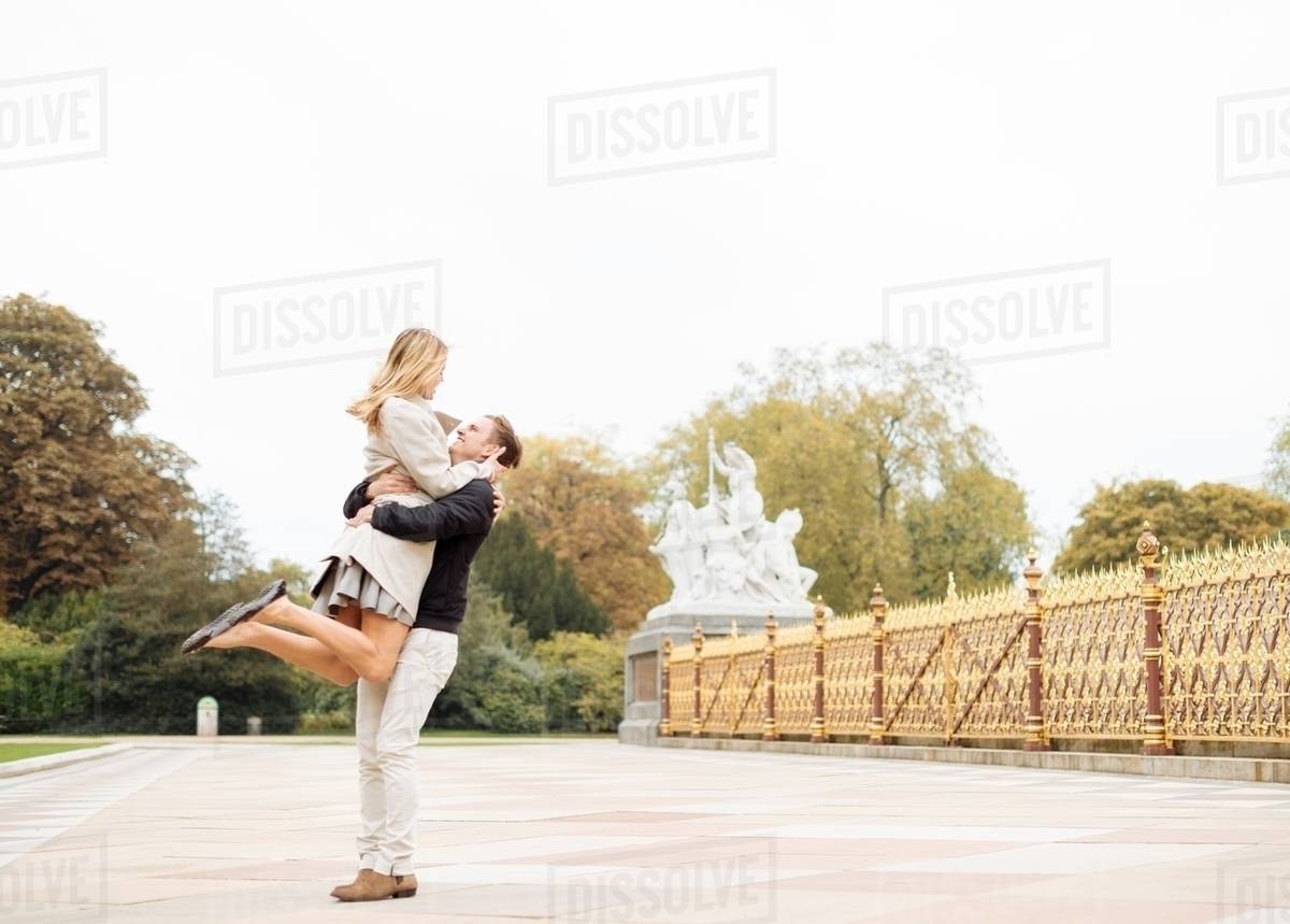 Romantic young man lifting up girlfriend in park - Stock Photo - Dissolve