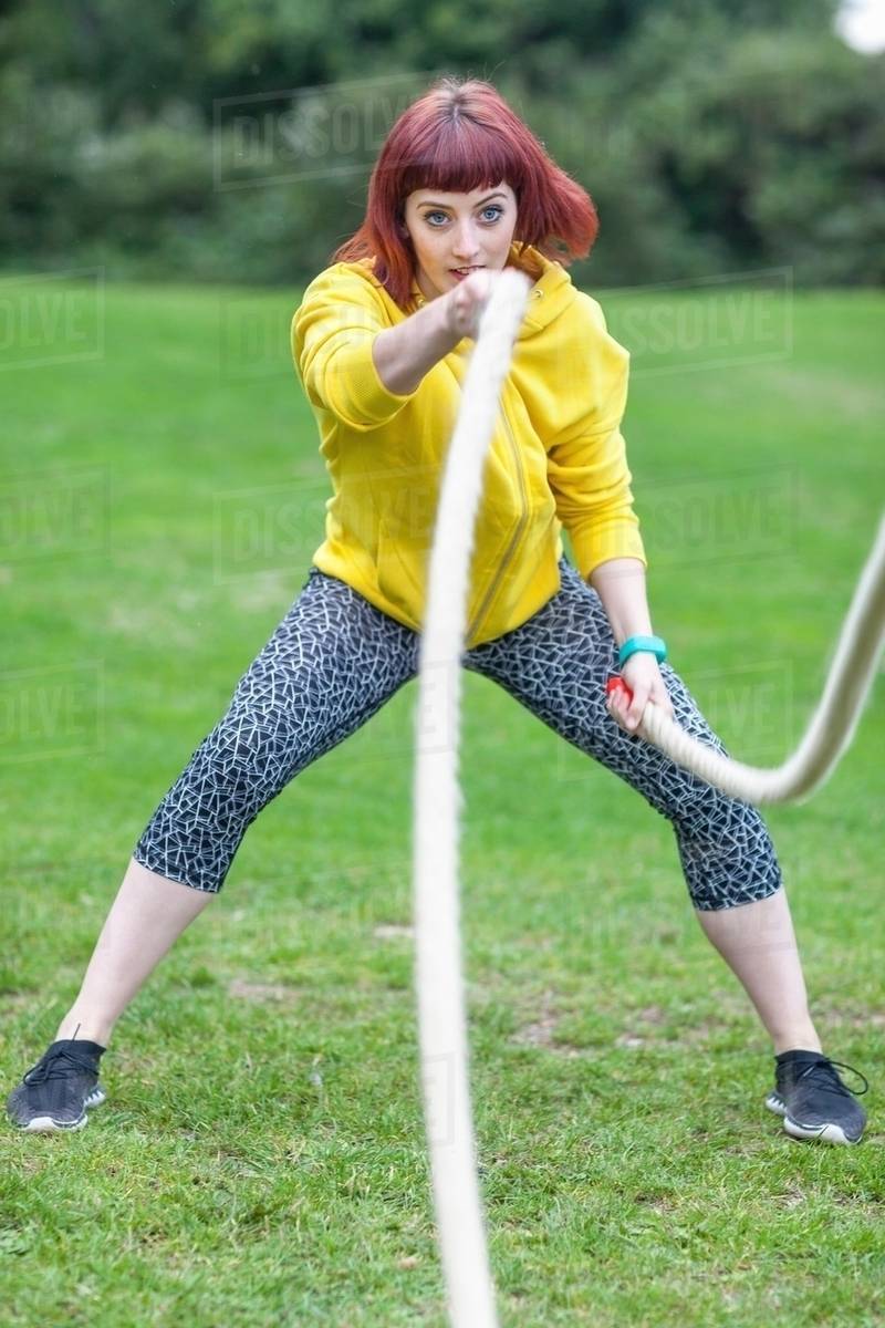 Young woman pulling rope on field - Stock Photo - Dissolve