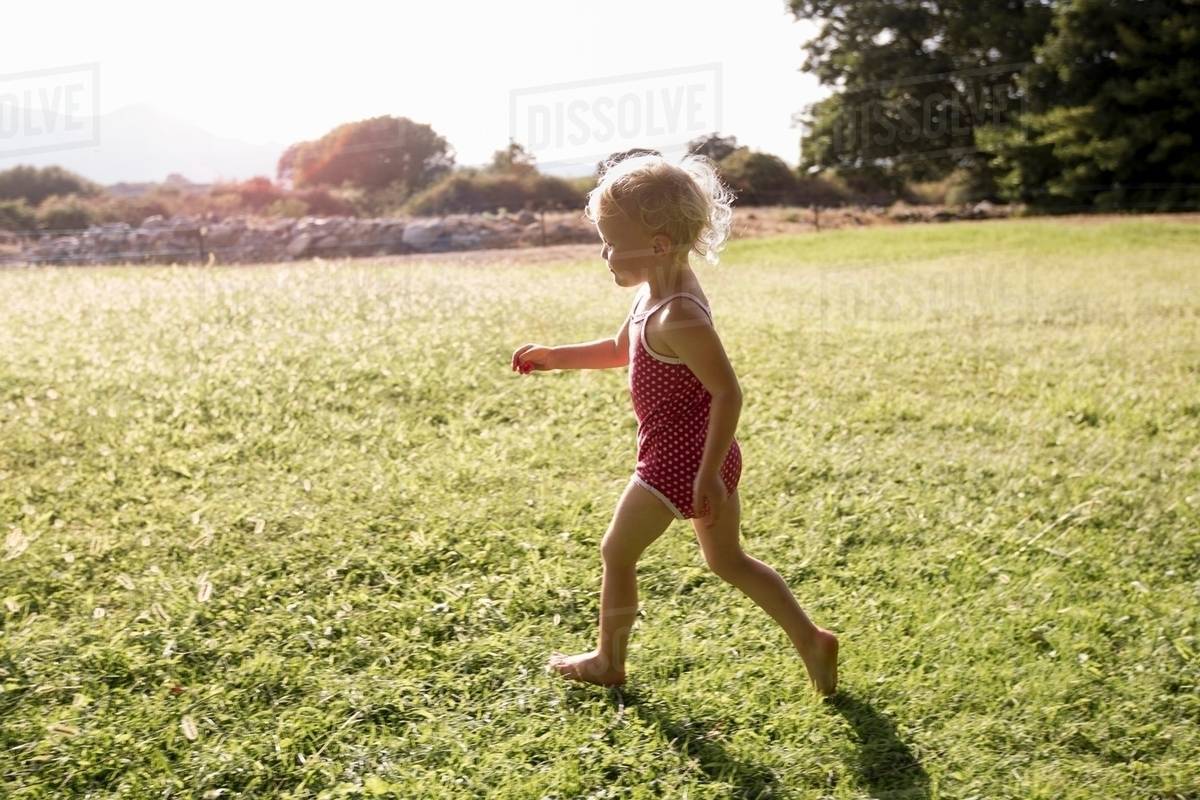 Female toddler running in field - Stock Photo - Dissolve