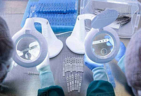 Workers inspecting surgical instruments in clean room of surgical ...