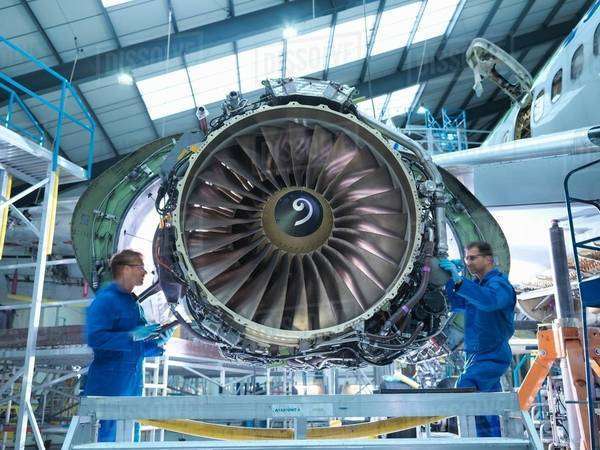 Engineers working on aircraft engine in aircraft maintenance factory ...