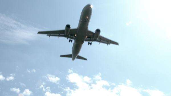 Commercial airline plane flying by overhead on sunny, blue sky day ...