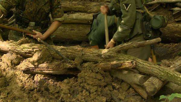 Young German soldiers in World War II dig a foxhole. They dump dirt ...