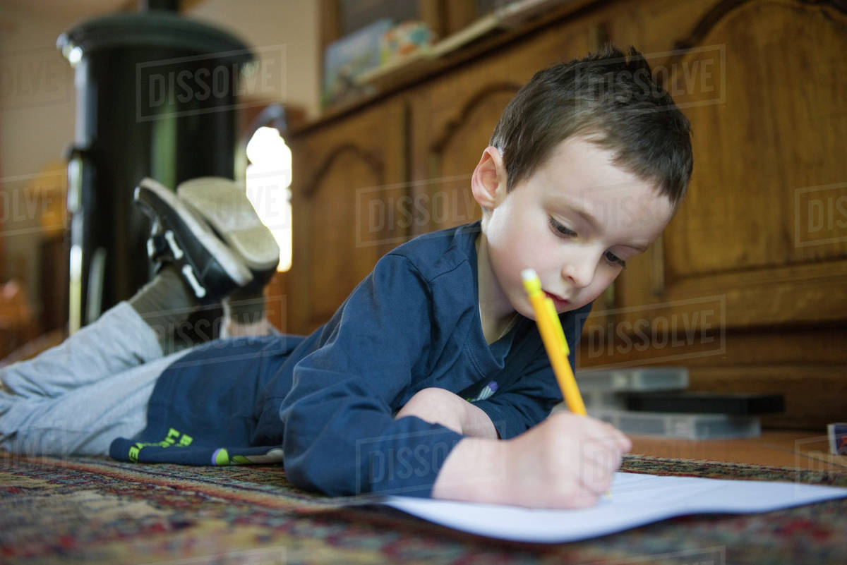 Boy lying on floor, writing on paper with pencil - Royalty-free Stock ...