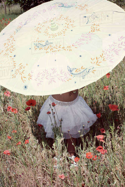 Little girl with parasol in meadow, mid section - Stock Photo - Dissolve