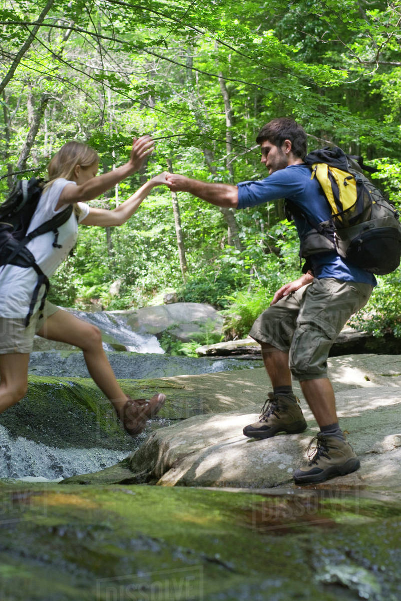 Man helping woman crossing stream - Royalty-free Stock Photo | Dissolve