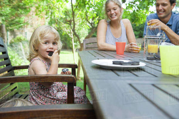 Little girl eating snack with her parents outdoors - Royalty-free Stock ...