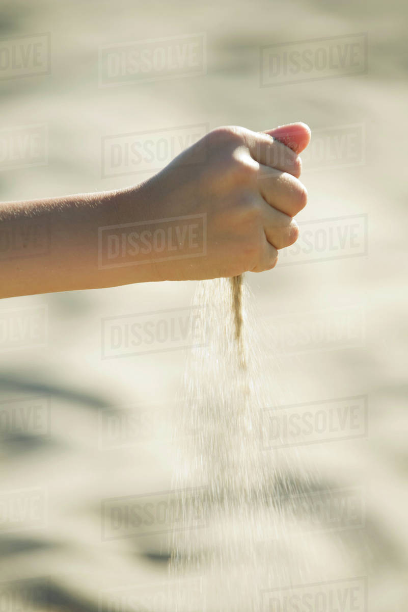 Sand spilling from child's hand - Stock Photo - Dissolve