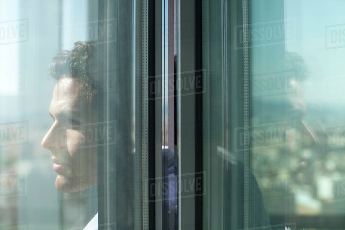 Man looking out of open window - Stock Photo - Dissolve