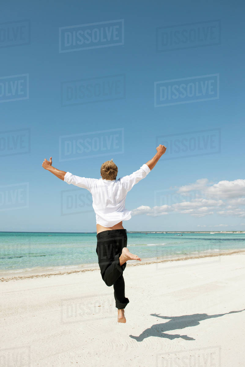 Man jumping midair on beach, rear view - Royalty-free Stock Photo ...