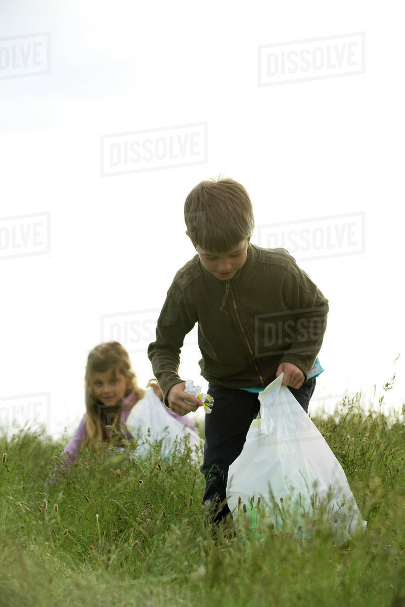 Children picking up trash in field - Royalty-free Stock Photo | Dissolve