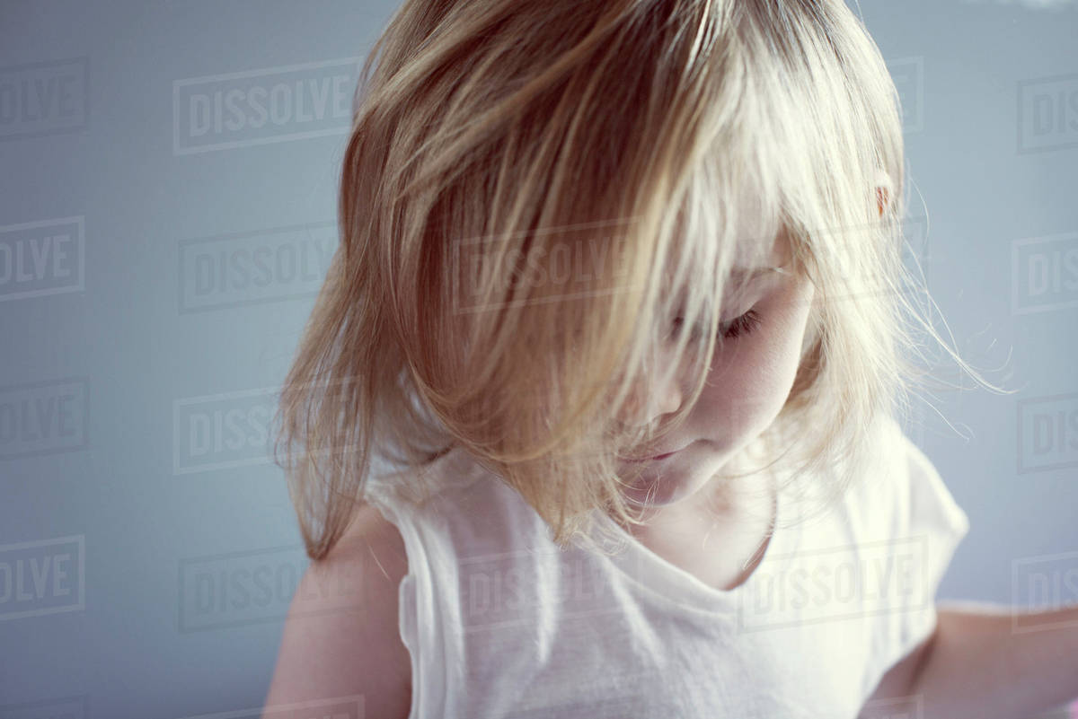 Little girl looking down, hair covering face - Stock Photo - Dissolve