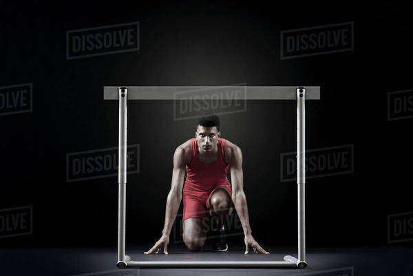 Male athlete at starting position in front of hurdle - Royalty-free ...