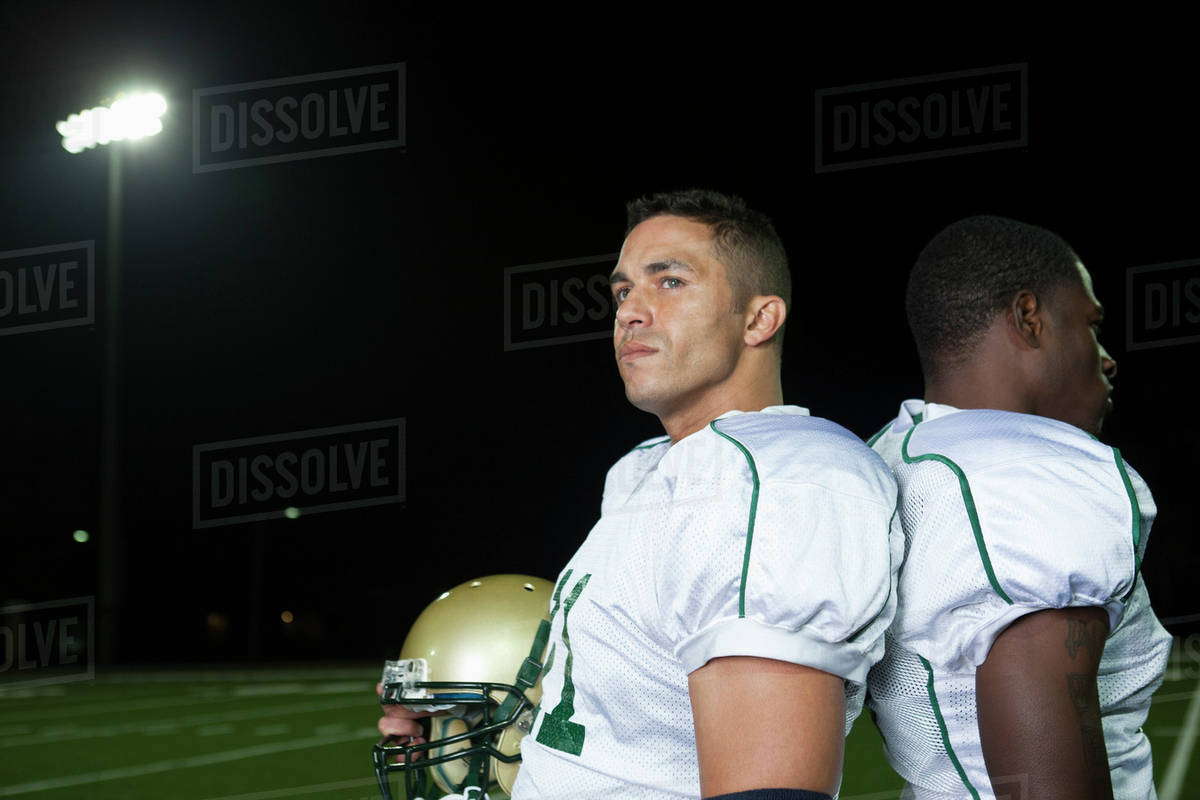 Football players standing back to back on field - Royalty-free Stock ...