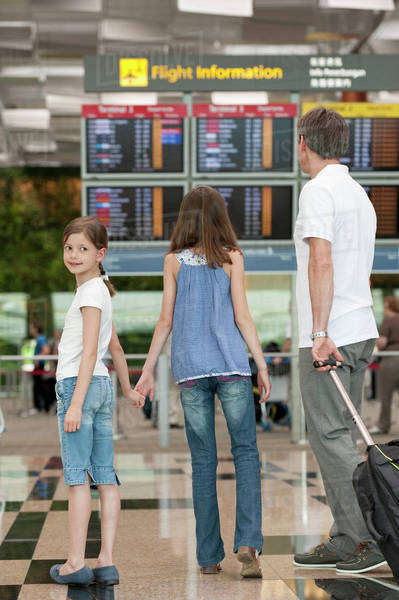 Family looking at arrival departure board in airport - Royalty-free ...