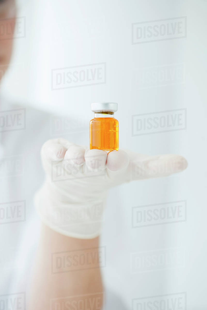 Scientist holding vial containing orange liquid - Royalty-free Stock ...