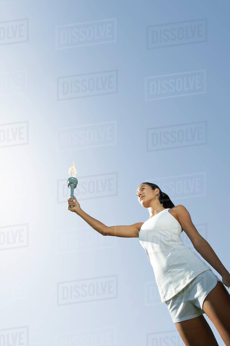 Female athlete holding up torch, low angle view - Royalty-free Stock ...