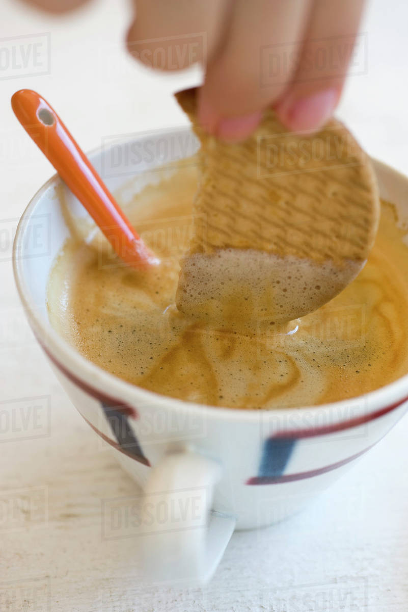 Dipping wafer in cup of cappuccino - Royalty-free Stock Photo | Dissolve
