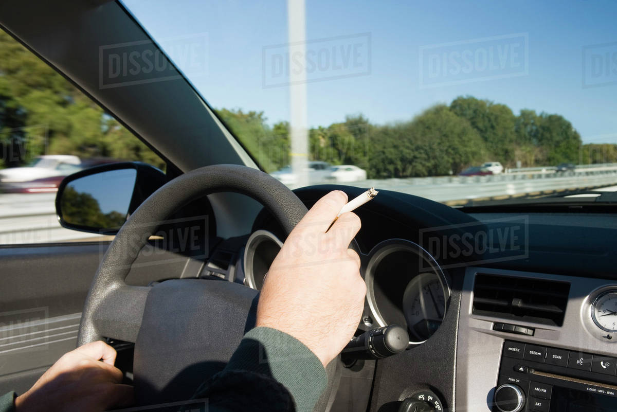 Smoking a cigarette while driving - Stock Photo - Dissolve
