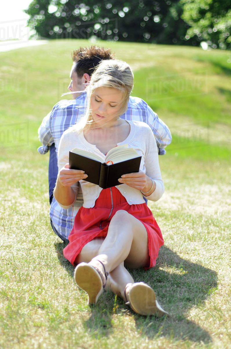Couple sitting back to back reading in park - Royalty-free Stock Photo ...