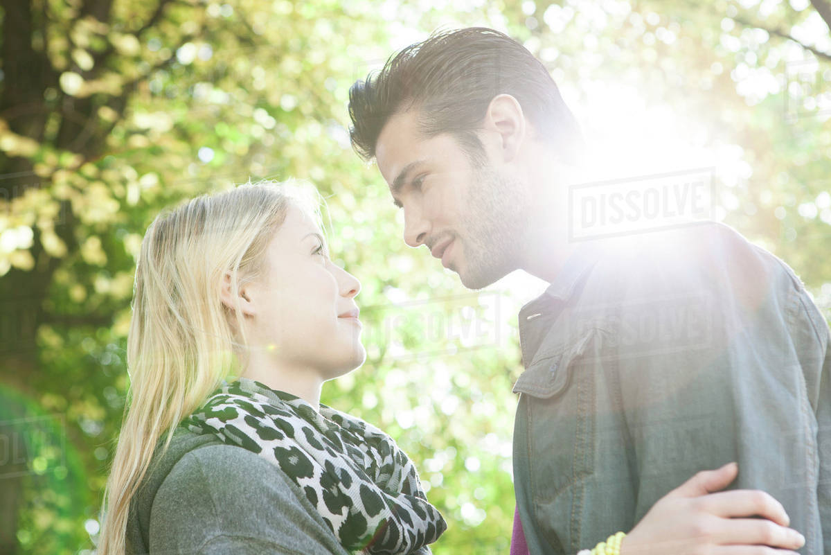 Couple standing together outdoors, looking into each other's eyes ...